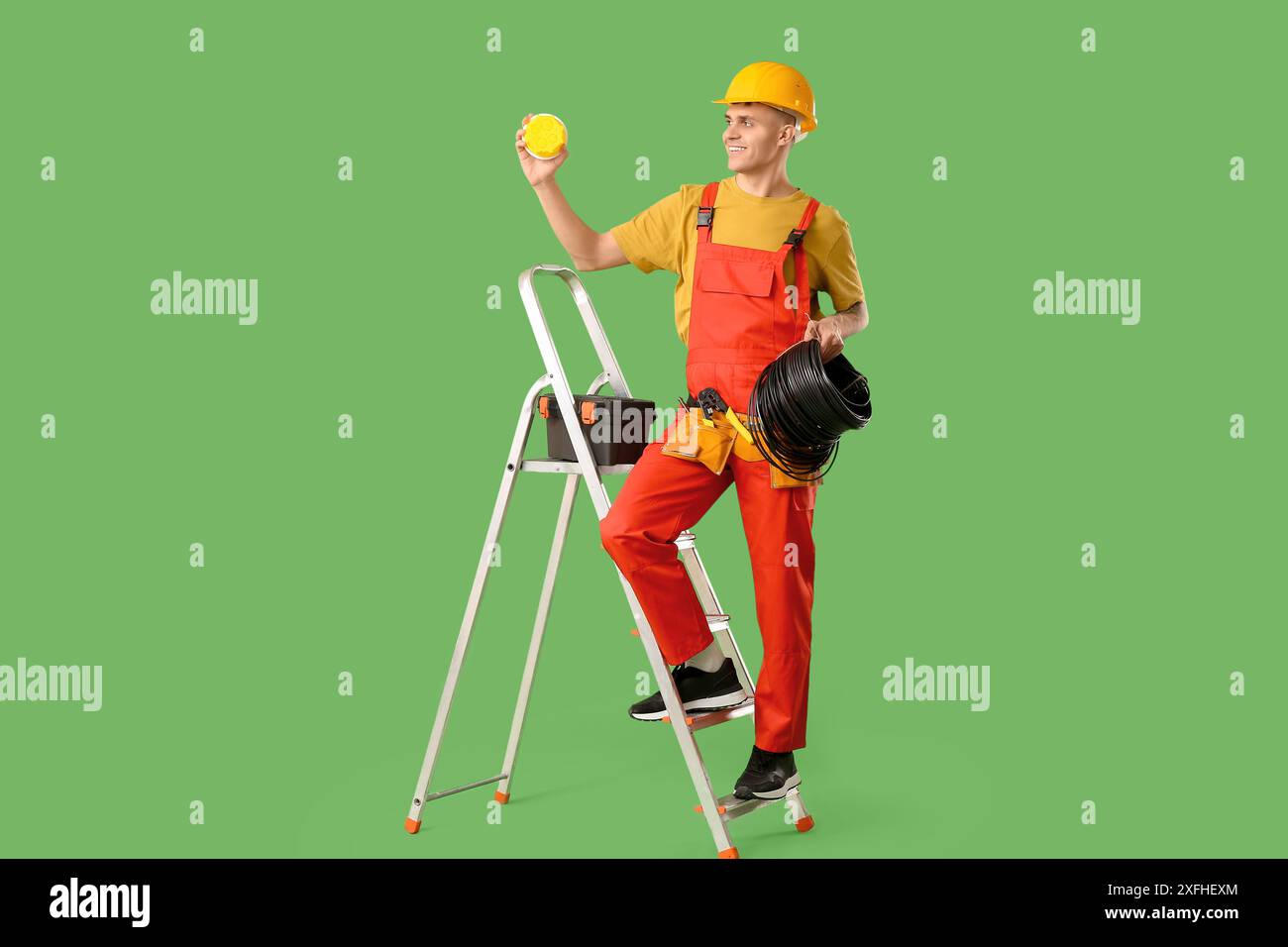 Young male electrician on stepladder with electrical junction box and ...