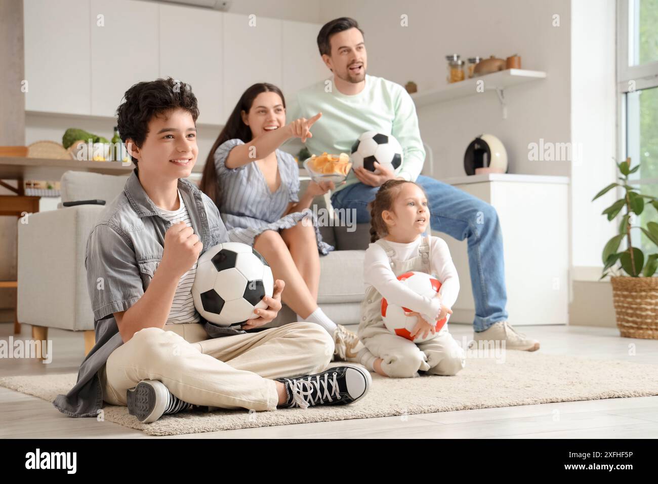 Teenage boy with soccer ball and his family watching football game at ...