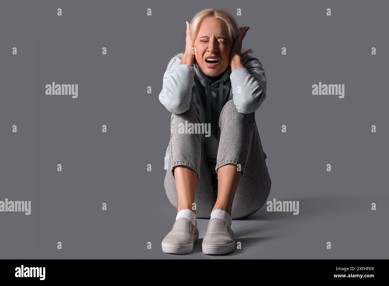 Mature woman having panic attack on grey background Stock Photo - Alamy