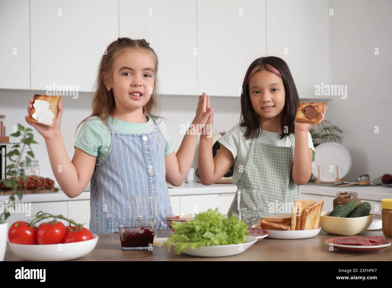 Cute little girls with tasty toasts giving each other high-five in ...
