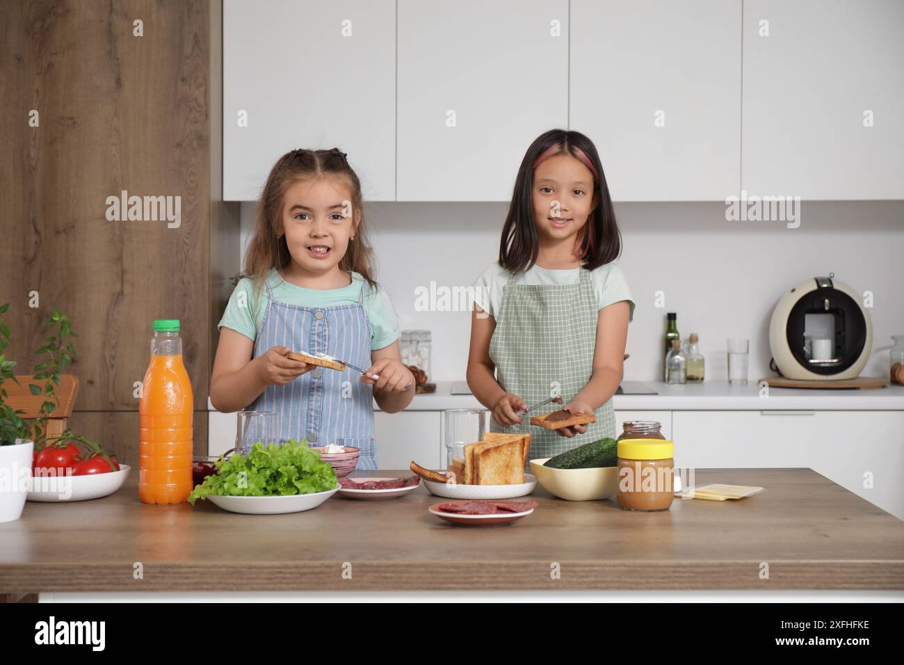 Cute little girls making toasts in kitchen Stock Photo - Alamy