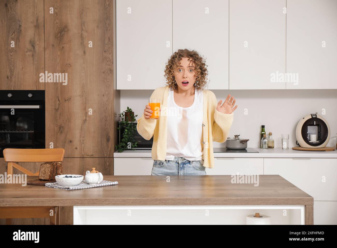 Shocked young woman spilled juice on her clothes in kitchen Stock Photo ...