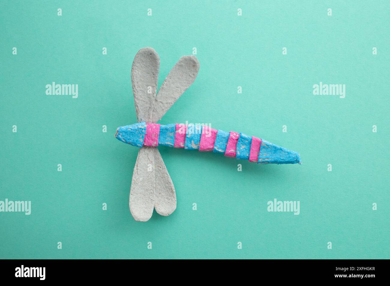 Close-up paper dragonfly on green surface. Handmade craft for kids ...