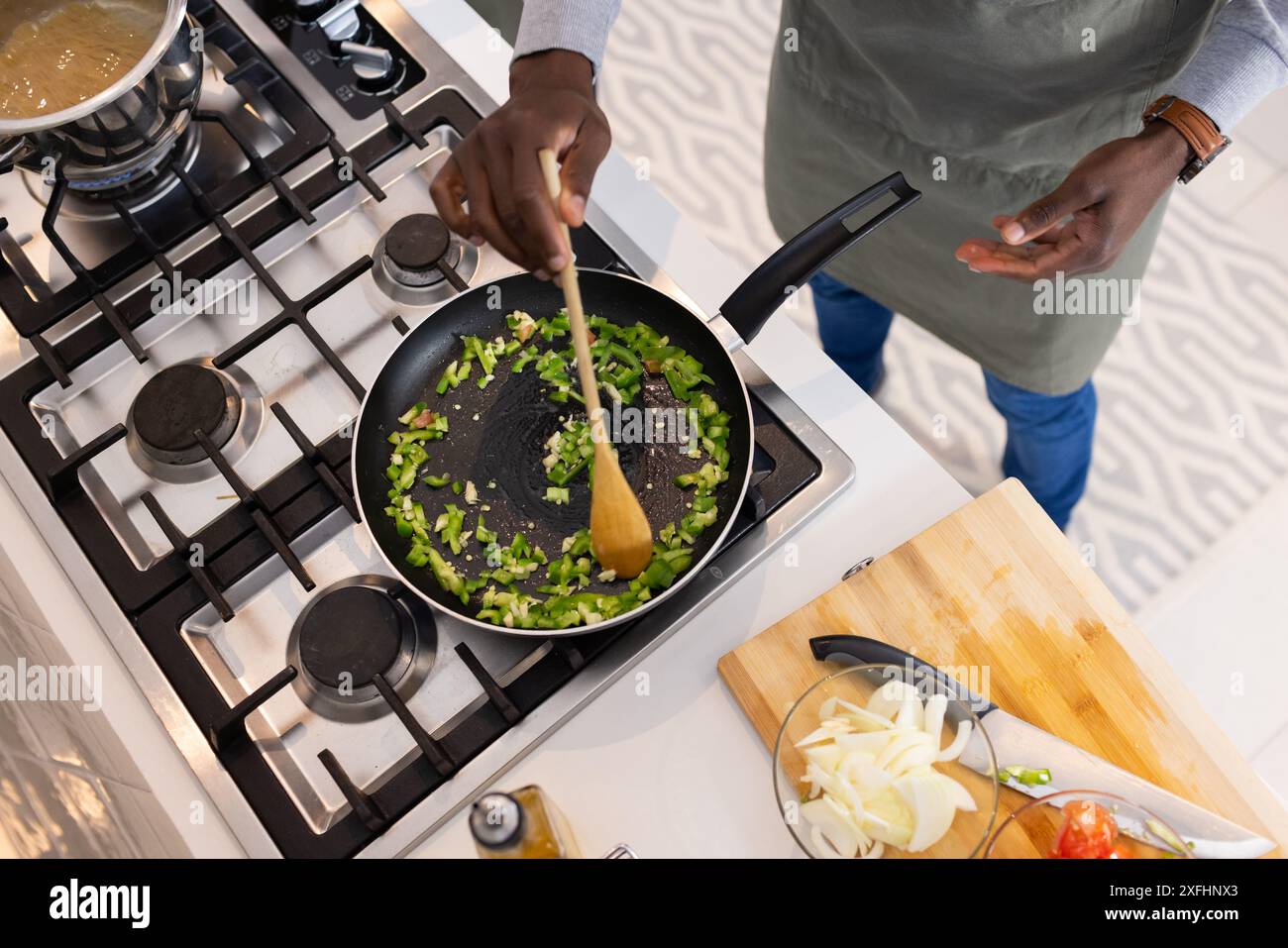 Cooking vegetables in frying pan, person stirring with wooden spoon in ...