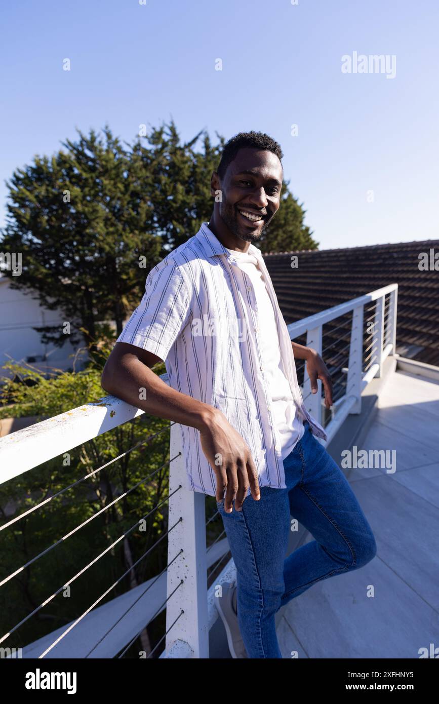 Smiling man leaning on balcony railing, enjoying outdoor home lifestyle ...
