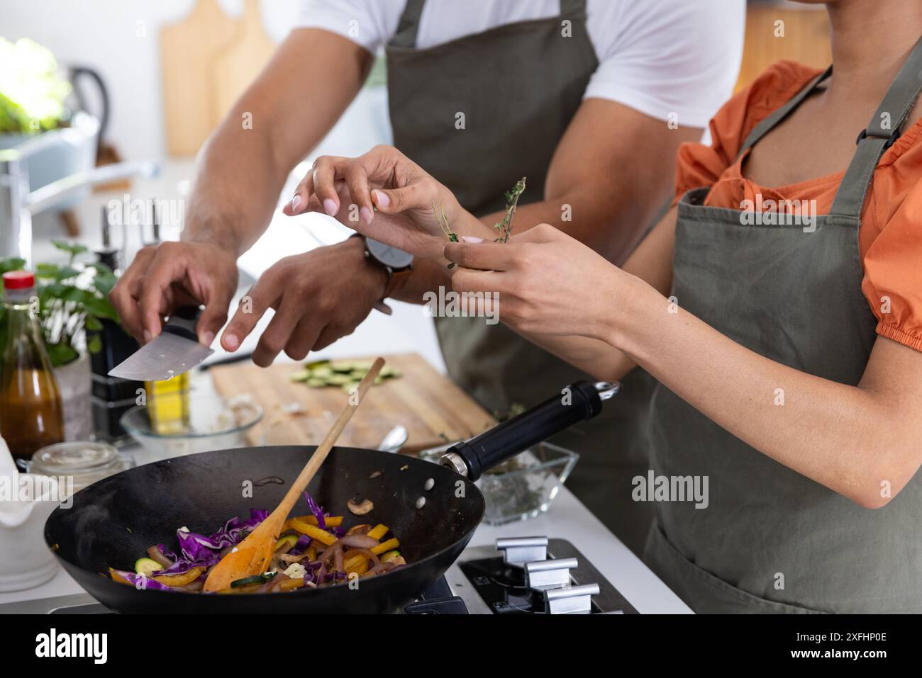 Cooking together, couple preparing vegetables in wok in modern kitchen ...
