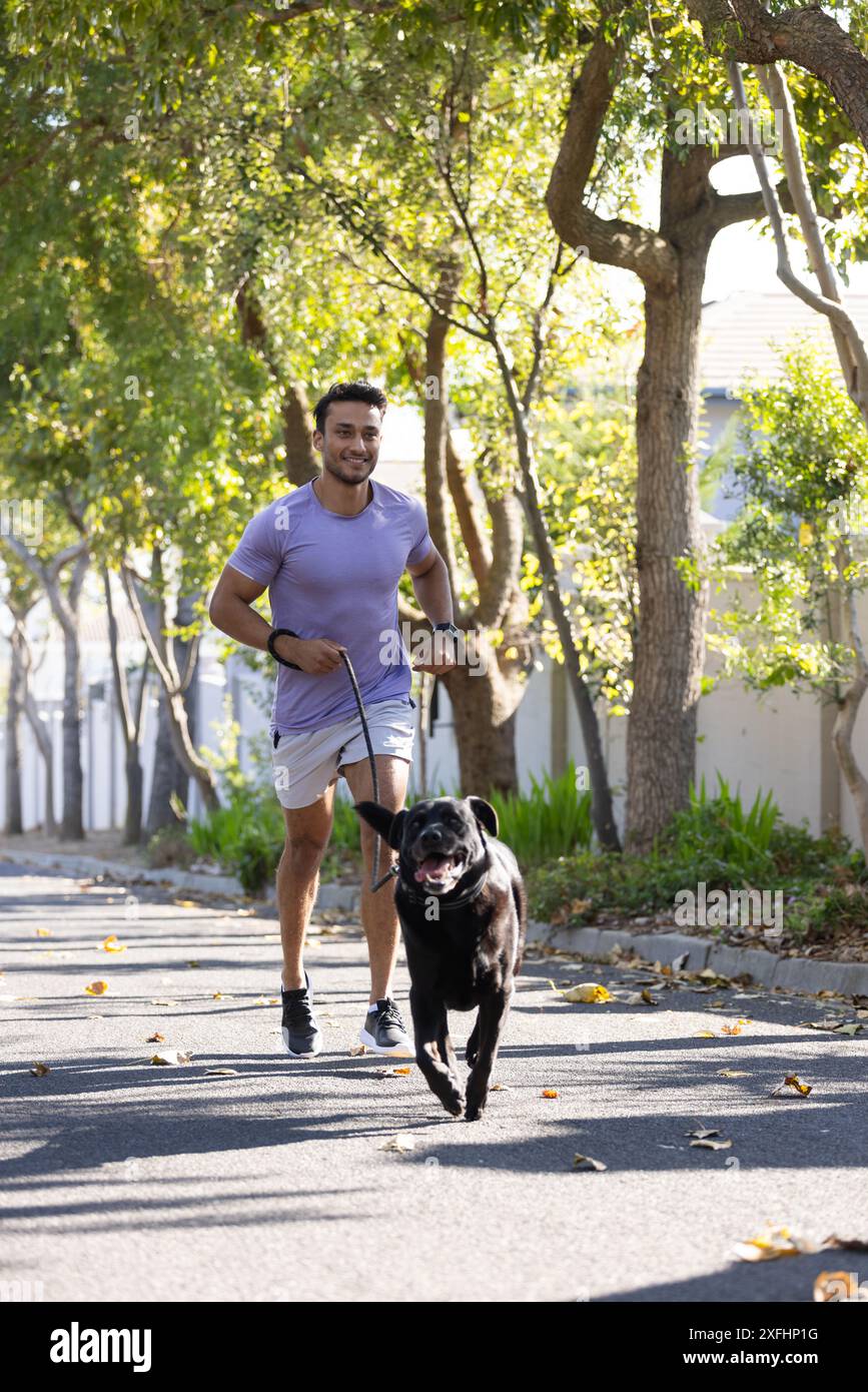 Jogging outdoors, man running with dog on leash in residential ...