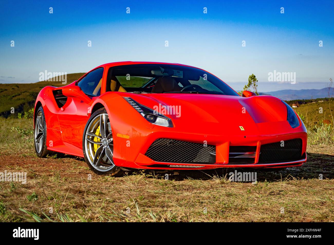 Red Ferrari 488 GTB parked on grass, mountains landscape background ...