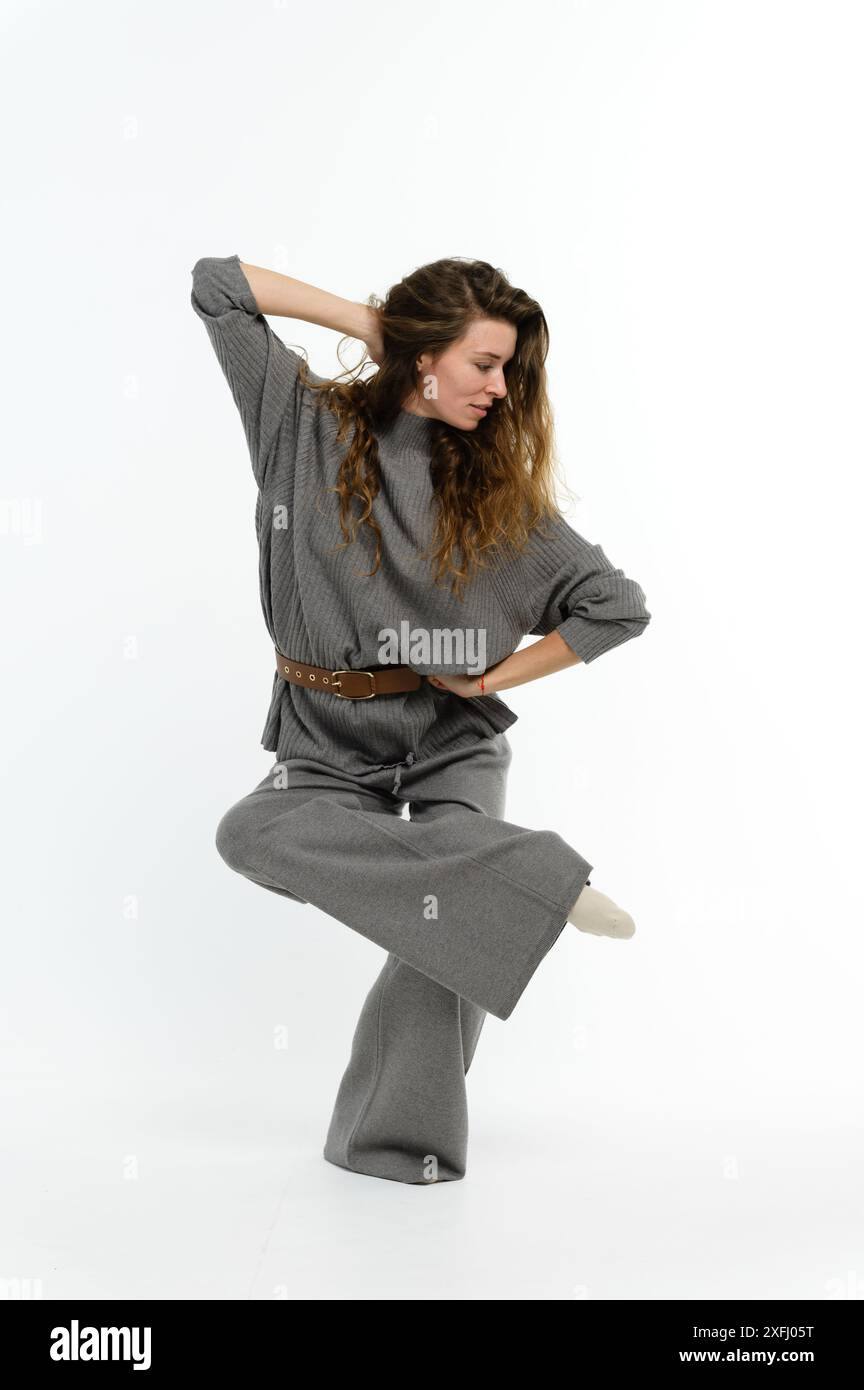 A young woman balances on one leg. The girl dances on a white ...