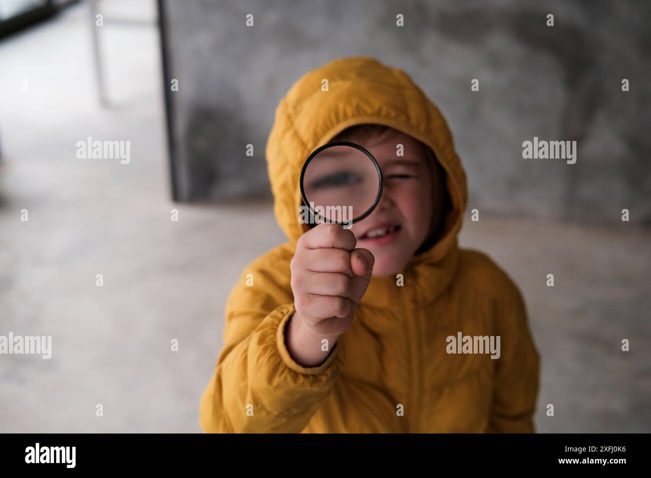 Portrait of a boy from elementary school who holds a magnifying glass ...
