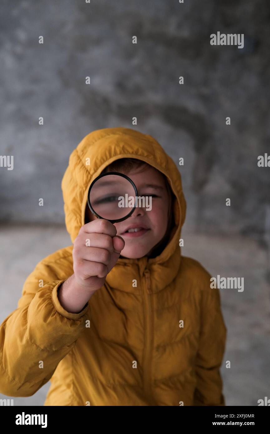 Portrait of a boy from elementary school who holds a magnifying glass ...