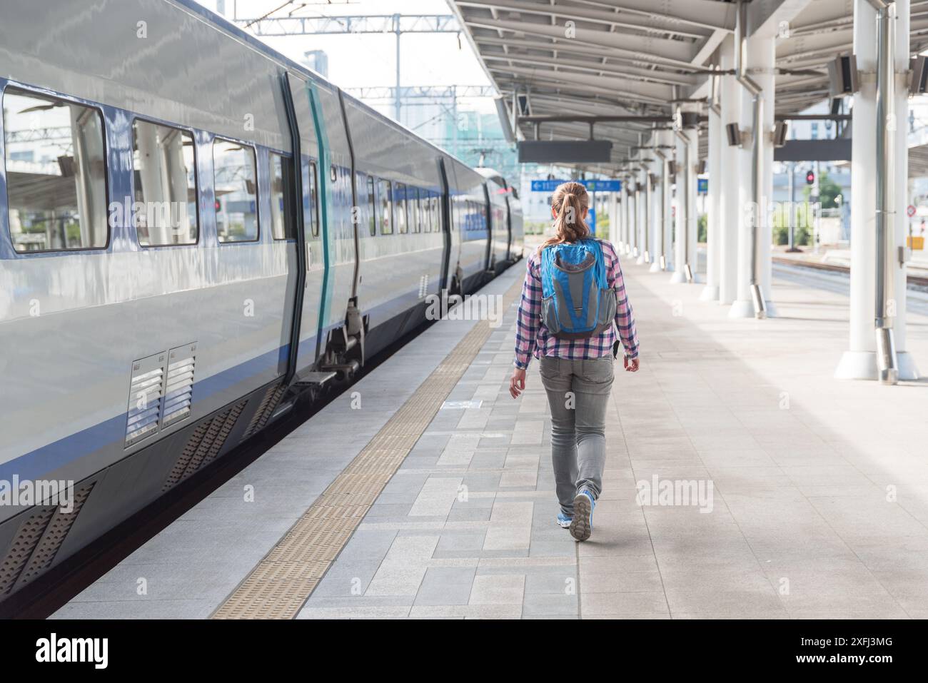 Young woman walking along platform to catch train. Female tourist with ...