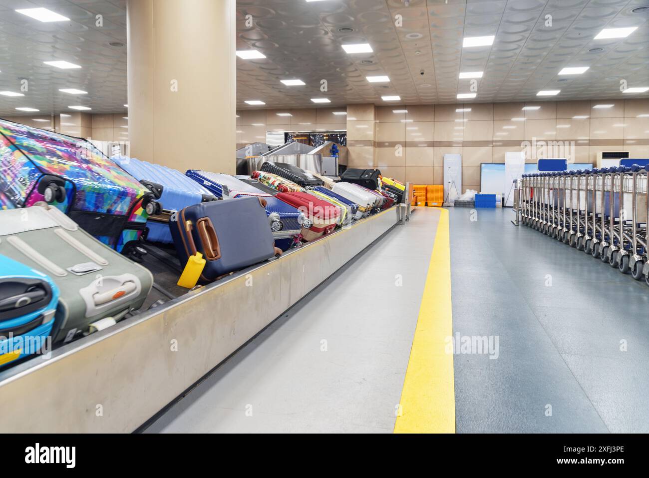 Colorful suitcases on luggage conveyor belt and row of trolleys at ...