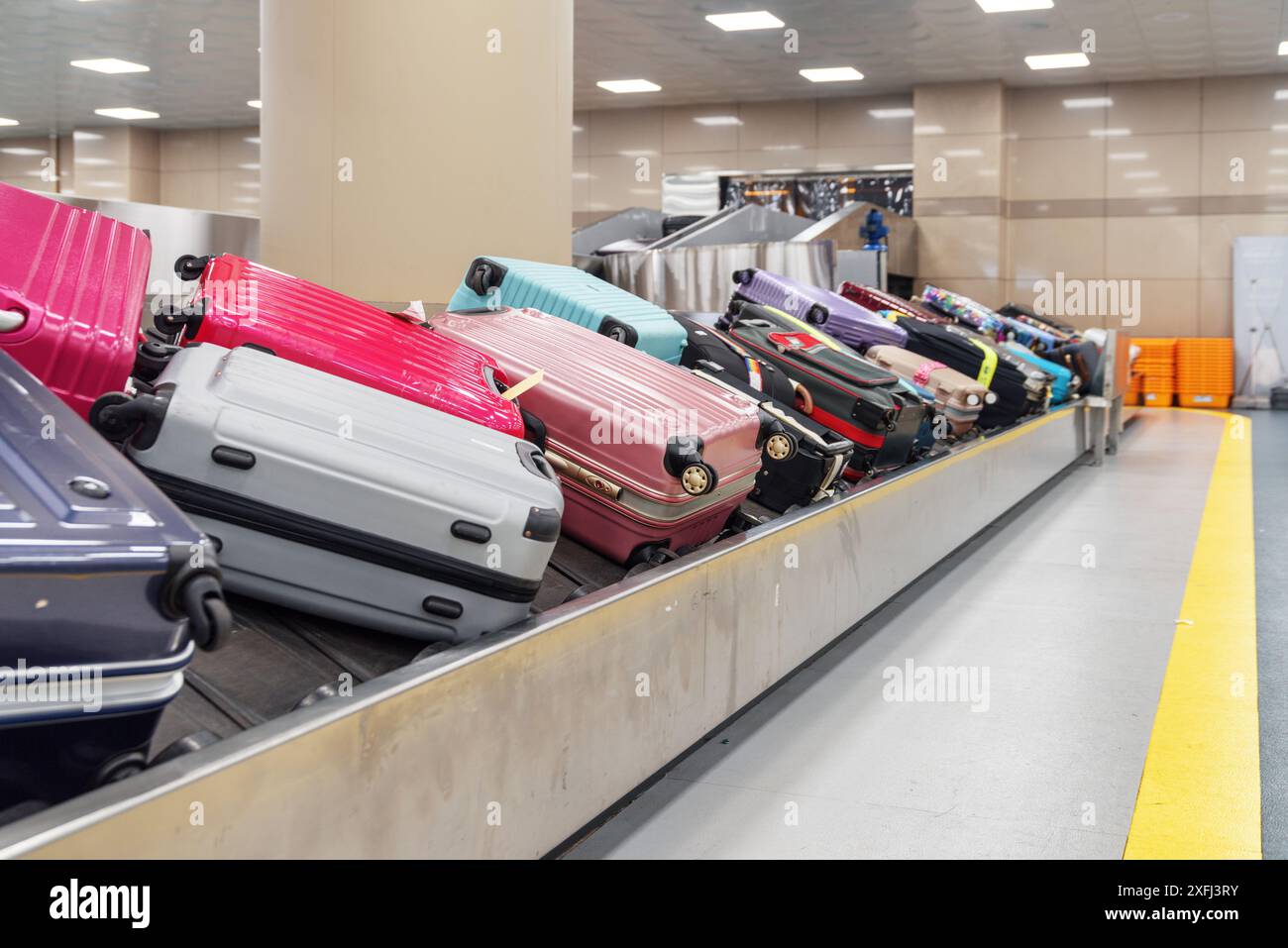 Bright pink suitcases on luggage conveyor belt at arrival area of ...