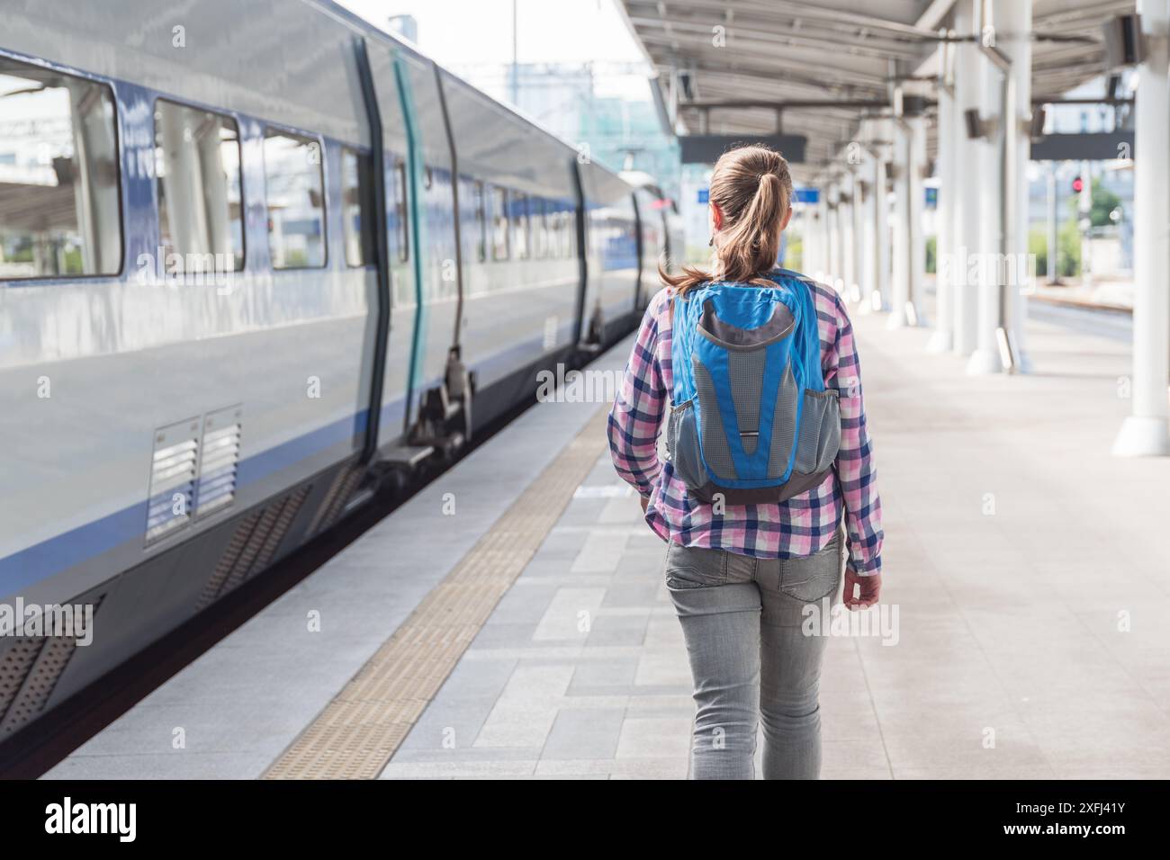 Young female tourist walking along platform to catch train. Girl with ...