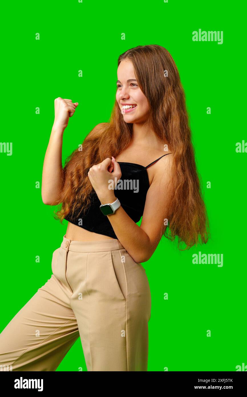 Young Woman Celebrating Success With Raised Fists Against Green Screen ...