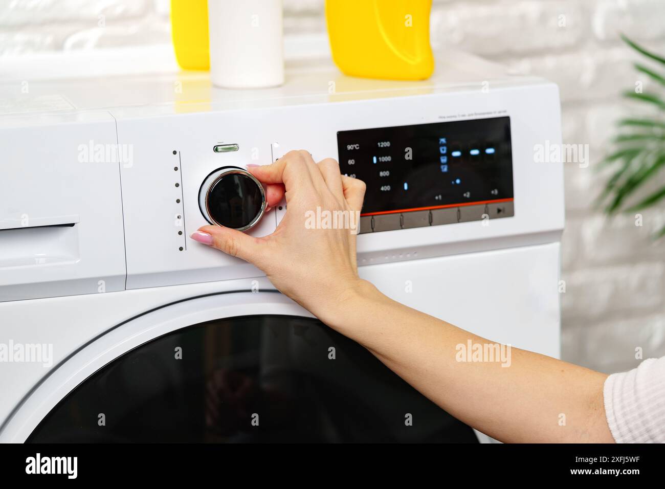 Woman Setting Washing Machine Cycle in Laundry Room Stock Photo - Alamy