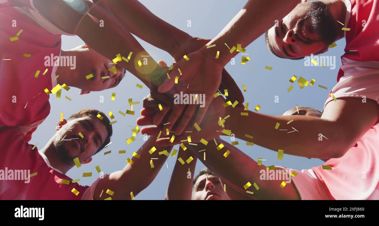 Image of confetti falling over male football team stacking hands on ...