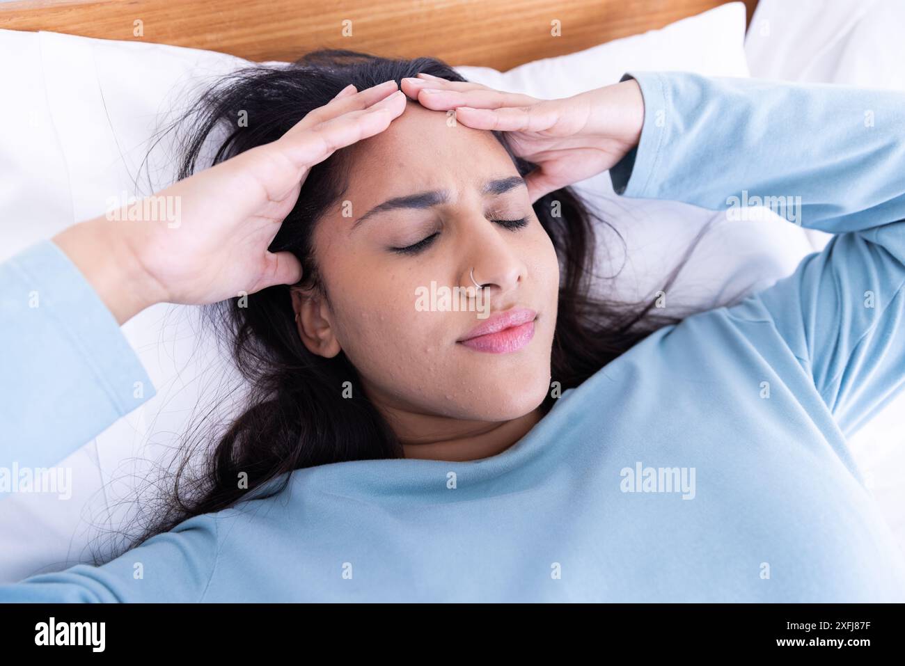 Lying in bed, woman holding head and experiencing headache or stress ...