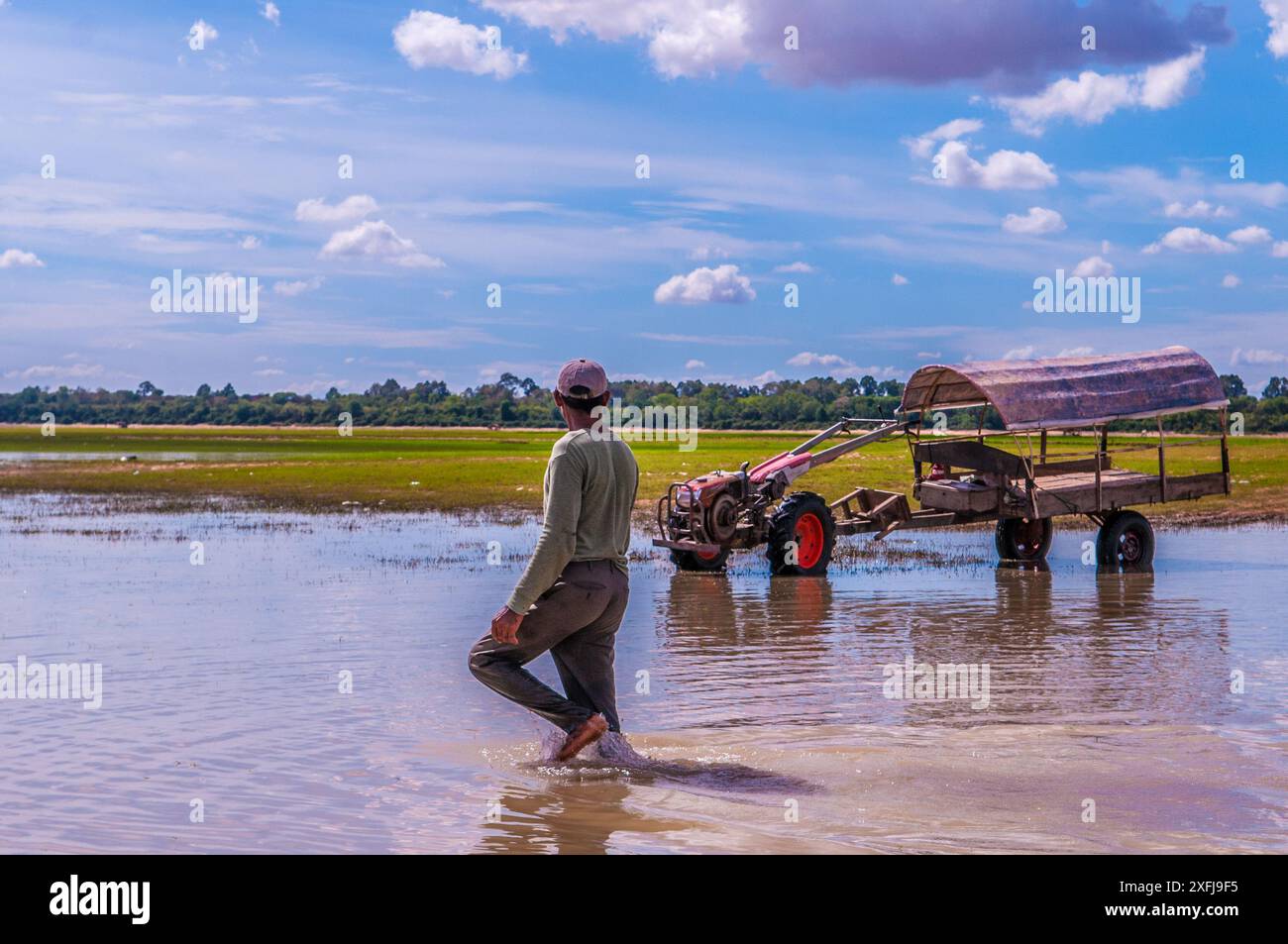 A Cambodian farmer wades past his tractor. West Baray Reservoir, Angkor ...