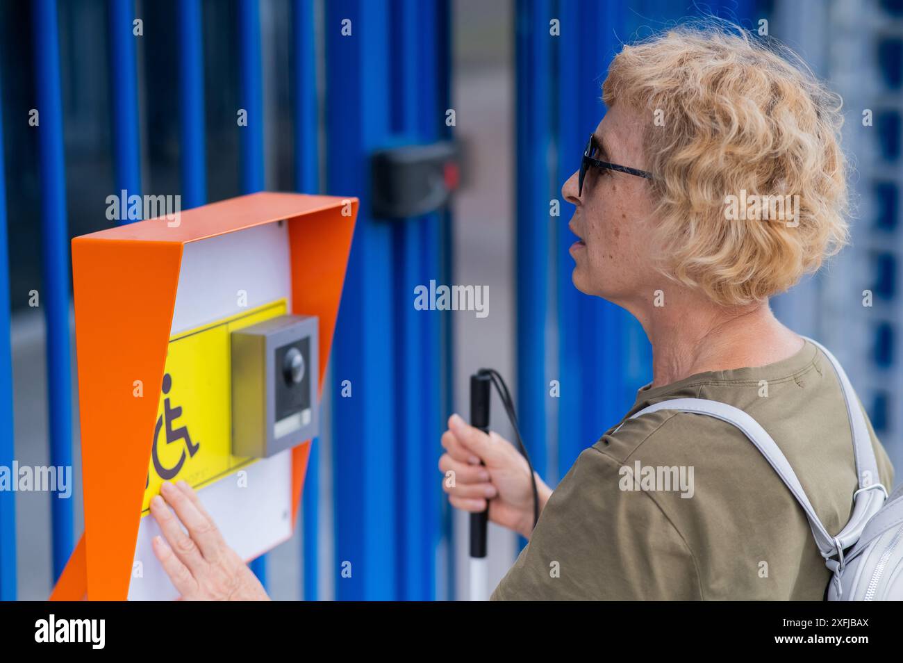 An elderly blind woman reading a text in braille. Button for calling ...