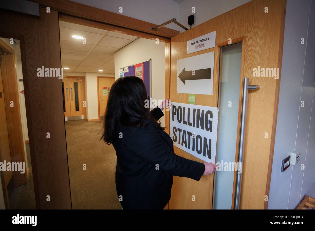 A member of the polling station team hangs a sign at the Agape Centre ...