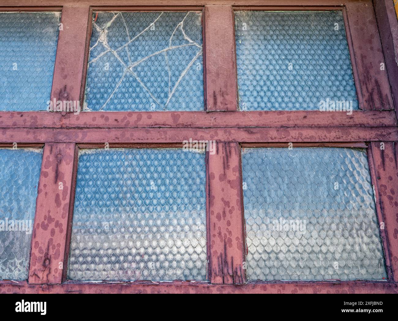 A cracked wire mesh glass window on the exterior wall of an abandoned ...