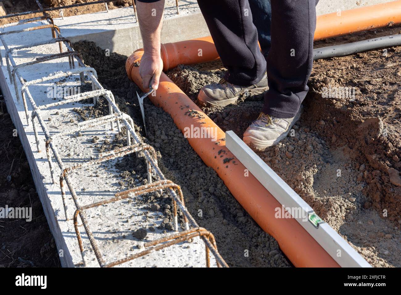Builder construction worker installing sewer pipes in the foundations ...
