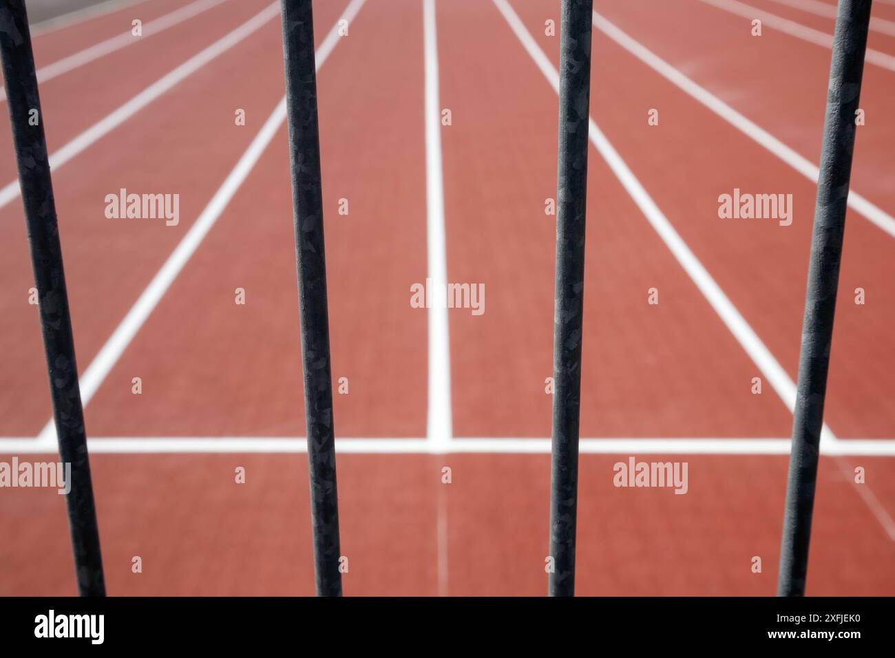 Athletics track lines behind fence bars Stock Photo - Alamy