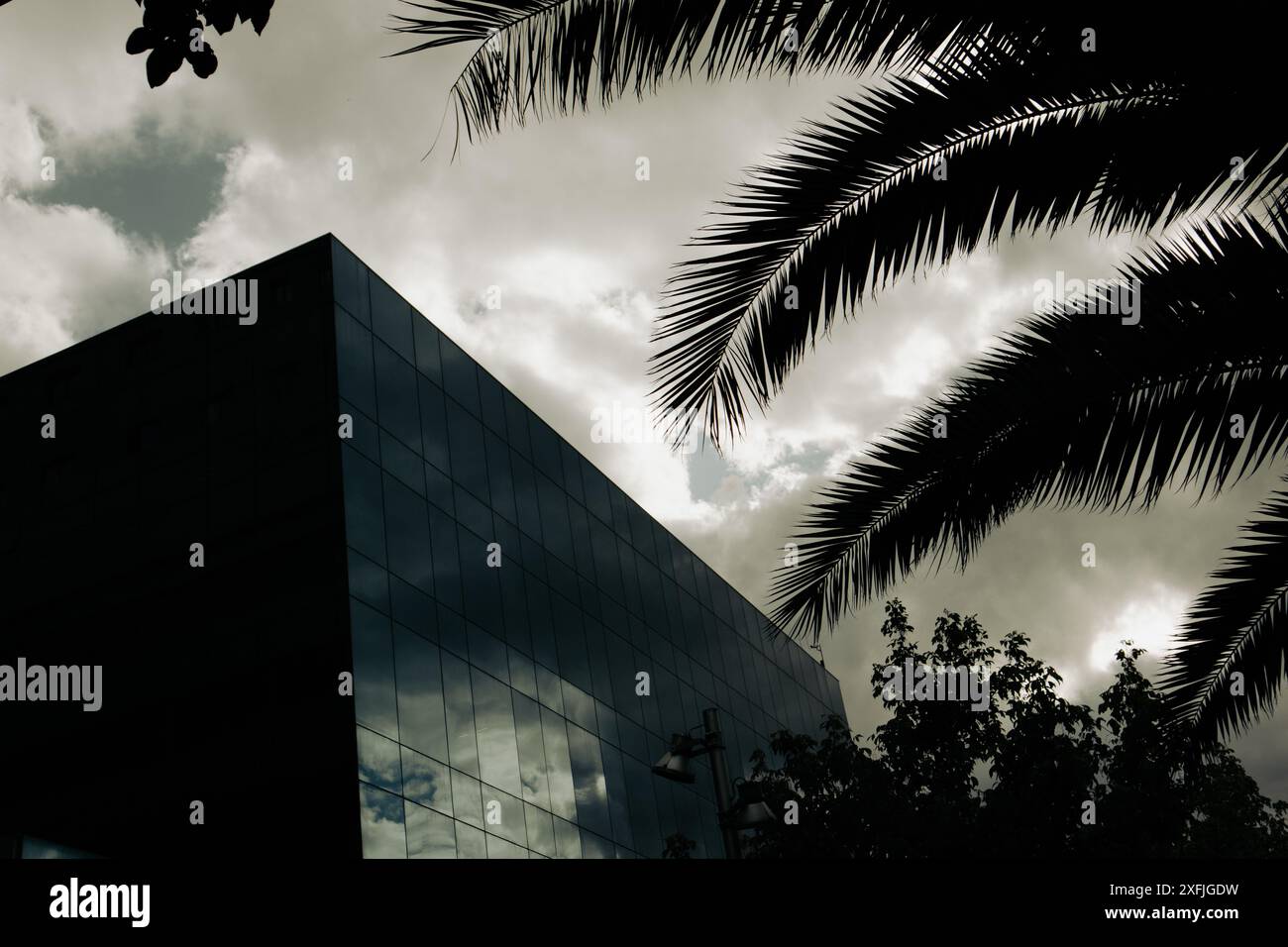 Modern high-rise building with glass facade and sky clouds reflection ...