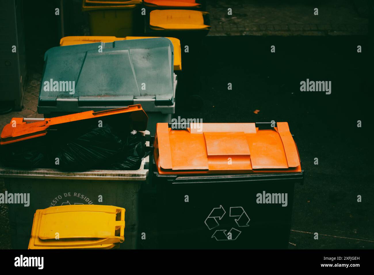 Colorful bright dumpsters for sorting miscellaneous waste in a back ...