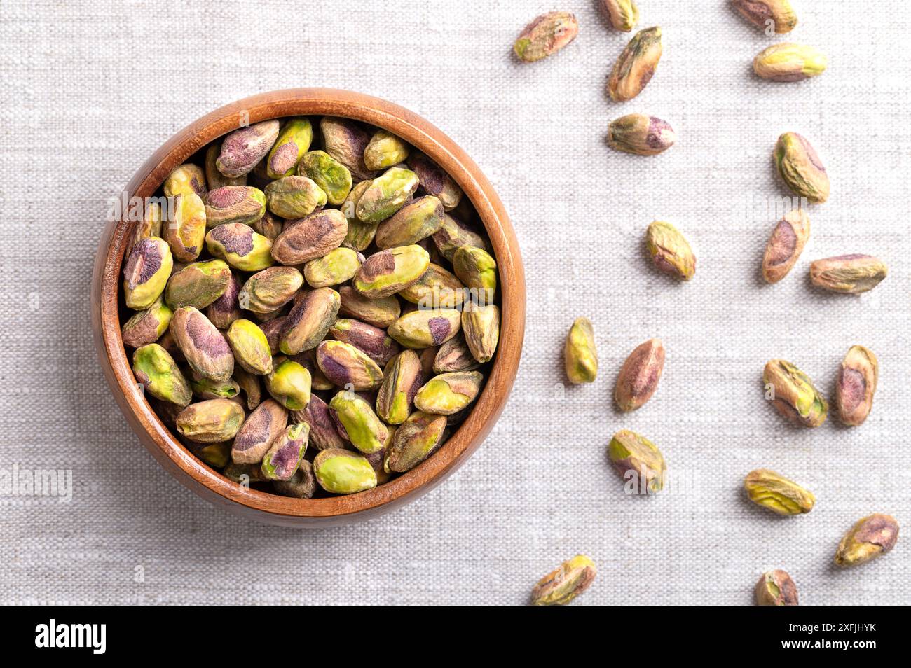 Pistachios kernels, roasted and salted nuts in a wooden bowl on linen ...