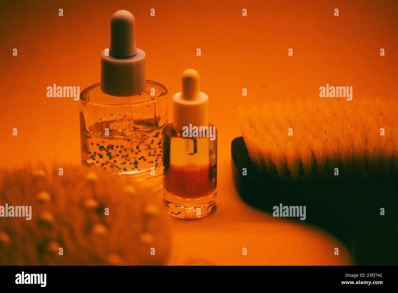 Cosmetics products and massage brushes in dark key on orange background ...