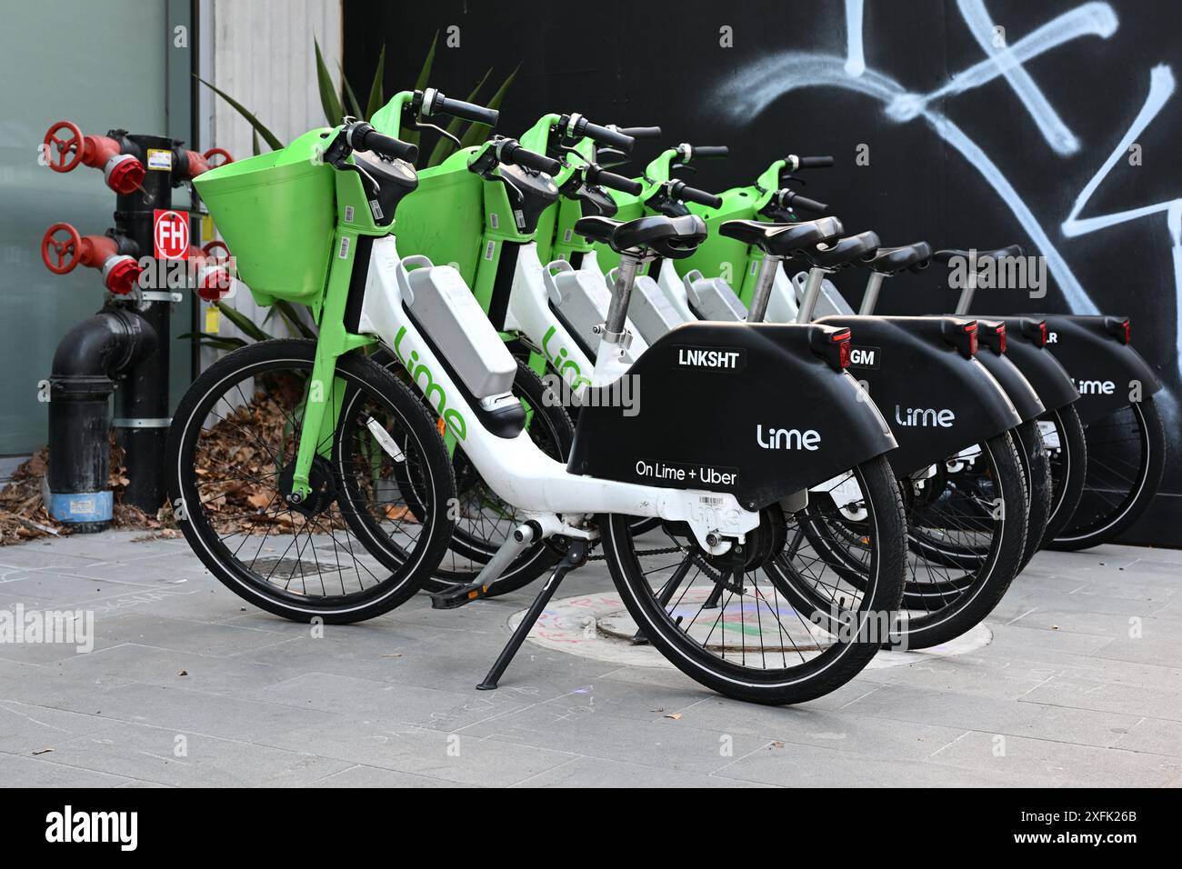 Side view of a row of five Lime bikes, neatly grouped together in a ...