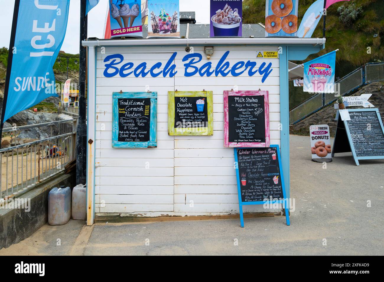 Handwritten signs around a fast food outlet on Towan Beach promenade in ...