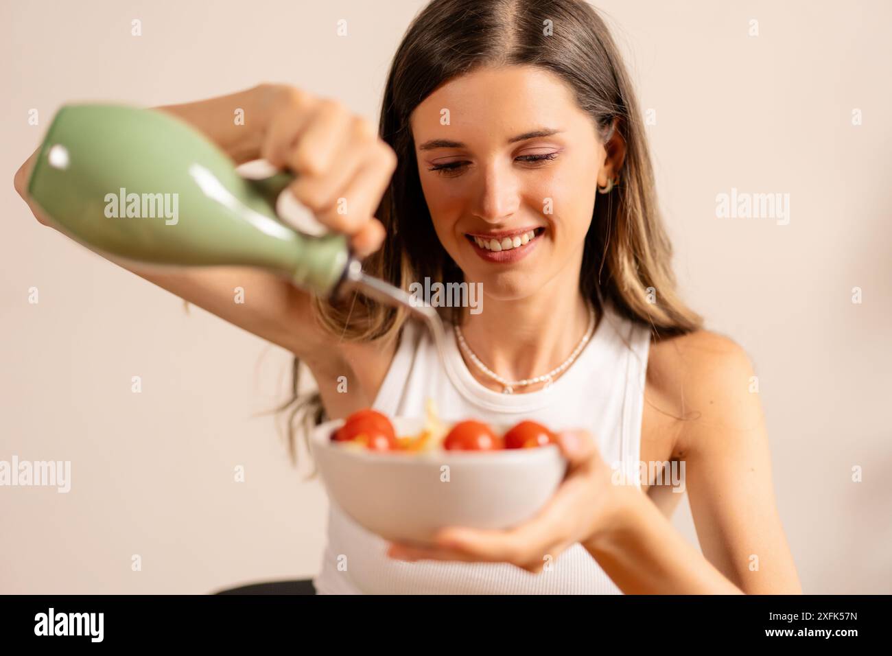 Woman pouring olive oil on salad - fresh and healthy preparation, enjoying fresh vegetables ...