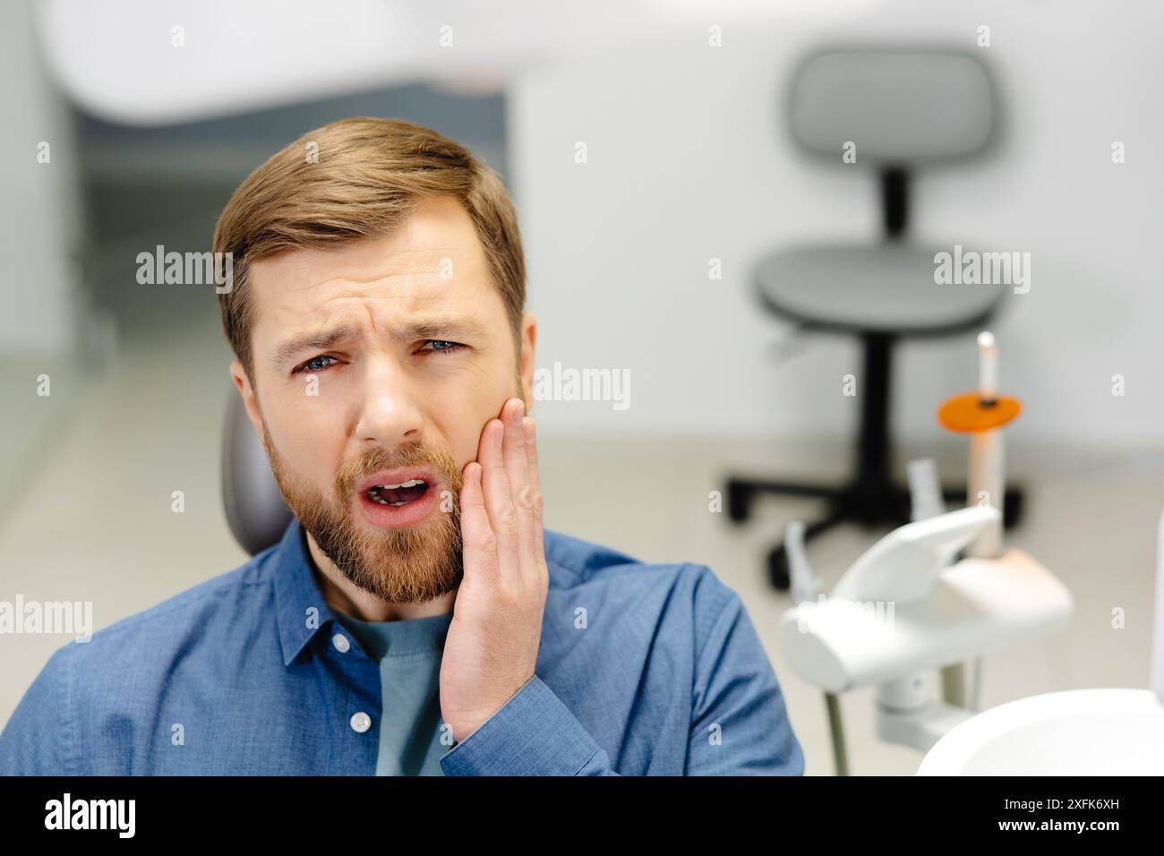 Sad man sitting in dental chair suffering from acute tooth pain ...