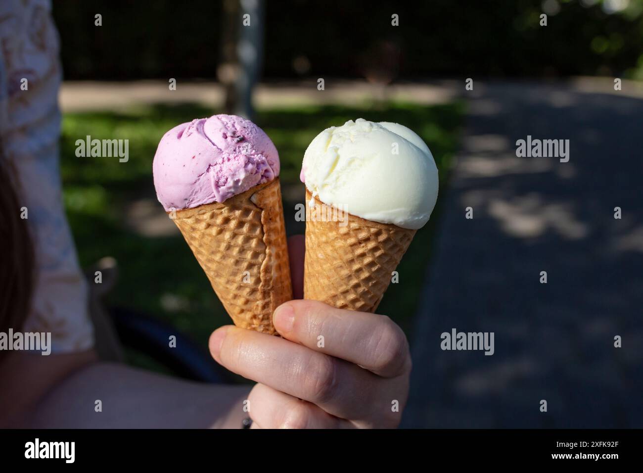 Woman hand holding two ice cream cones on defocused dark park ...