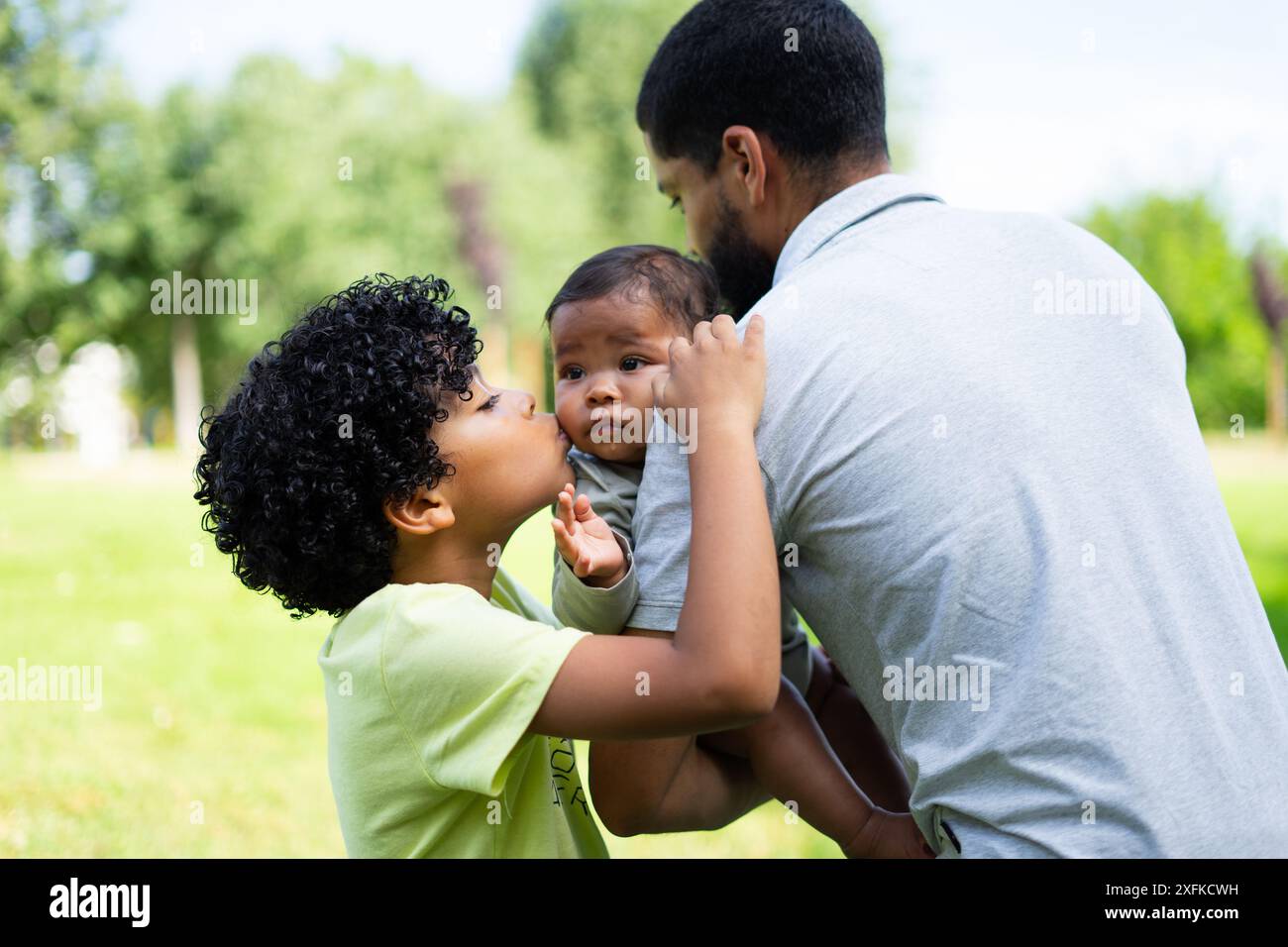 Latin family with a father holding his baby in his arms and his older ...