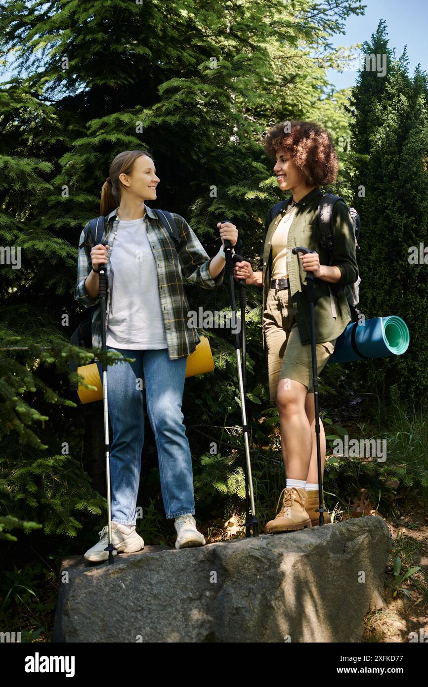 Two young women hike through the woods together, enjoying the beauty of ...