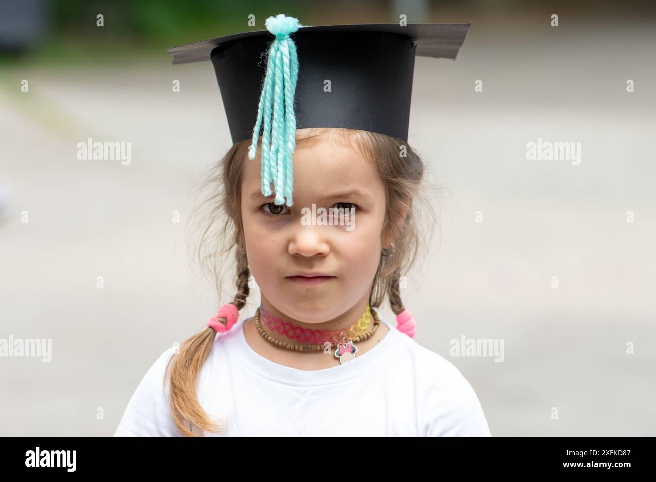 Portrait of a 6 years old girl in a graduation cap. Concept: a ...