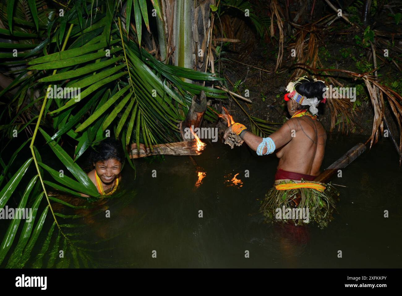 Mentawai women fishing at night, using burning wood for light to ...