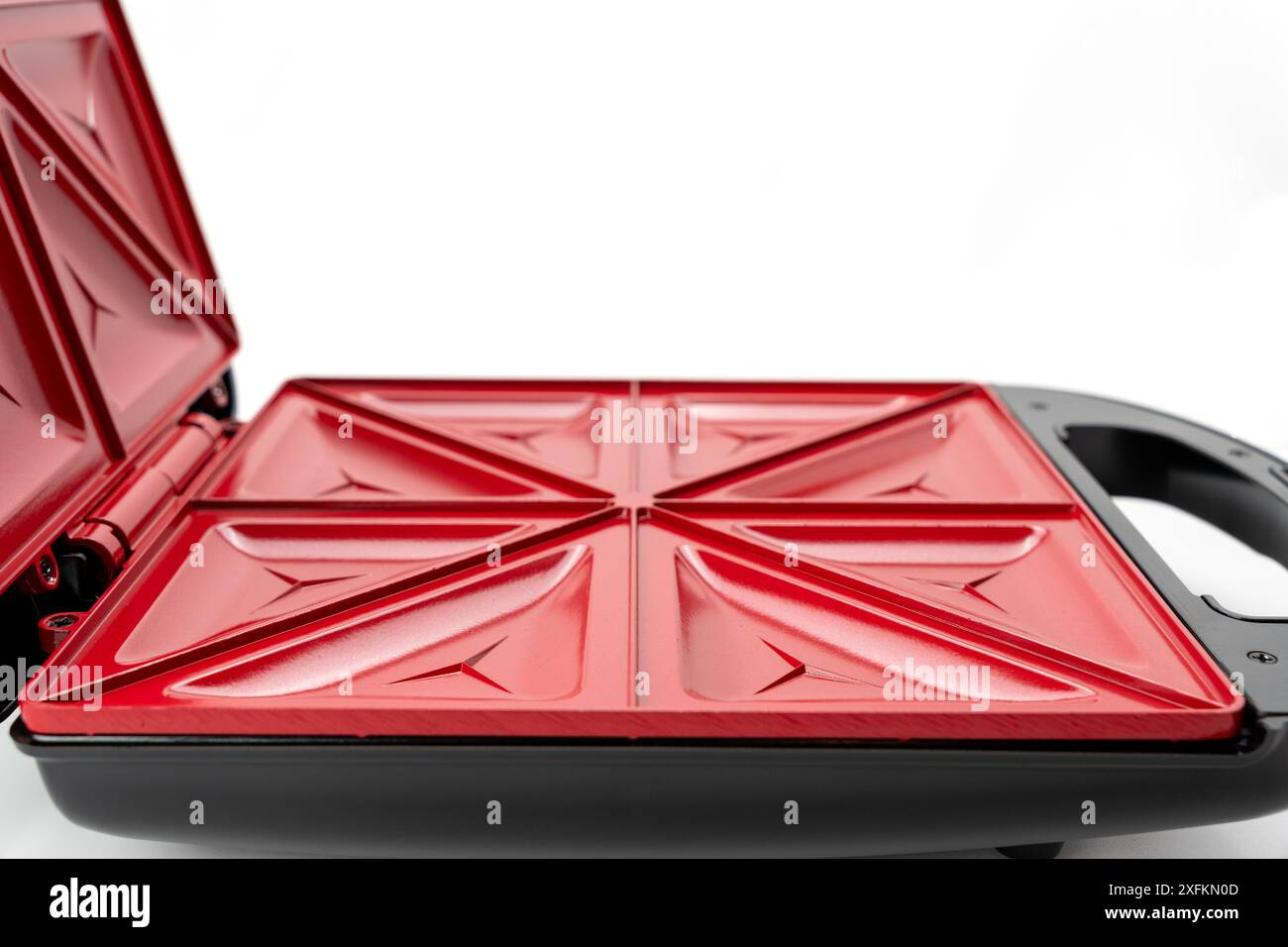 Red and black sandwich maker open. The sandwich maker is square and has ...
