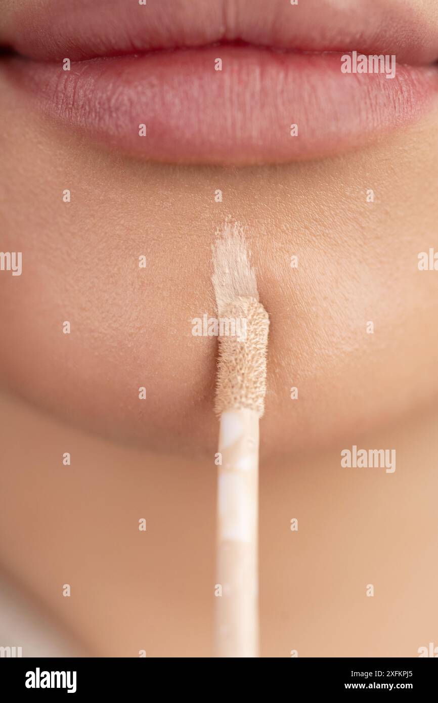 Girl uses concealer while applying foundation on her chin. Makeup ...