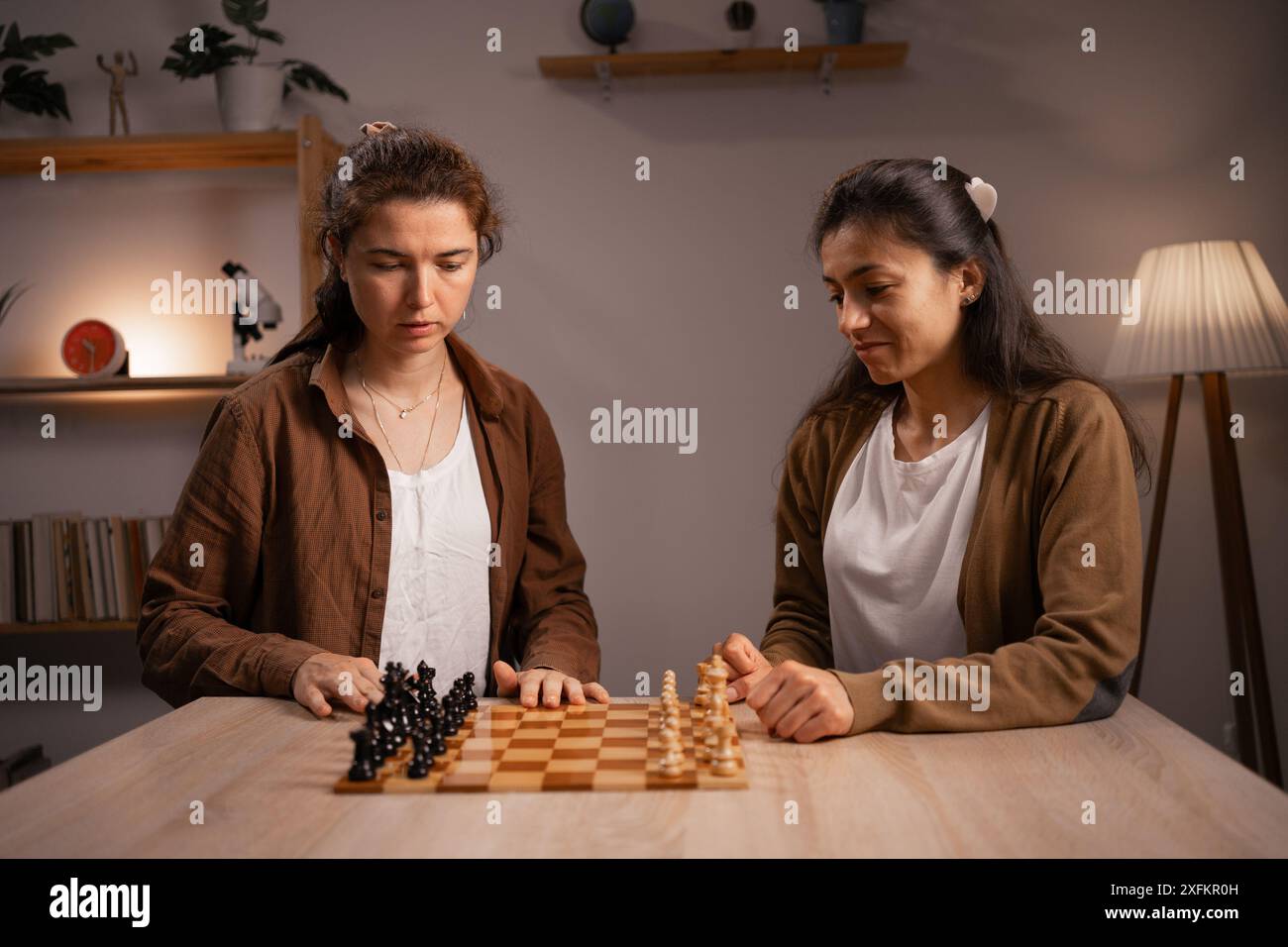 Battle at chessboard. Women play friendly chess match at home while ...
