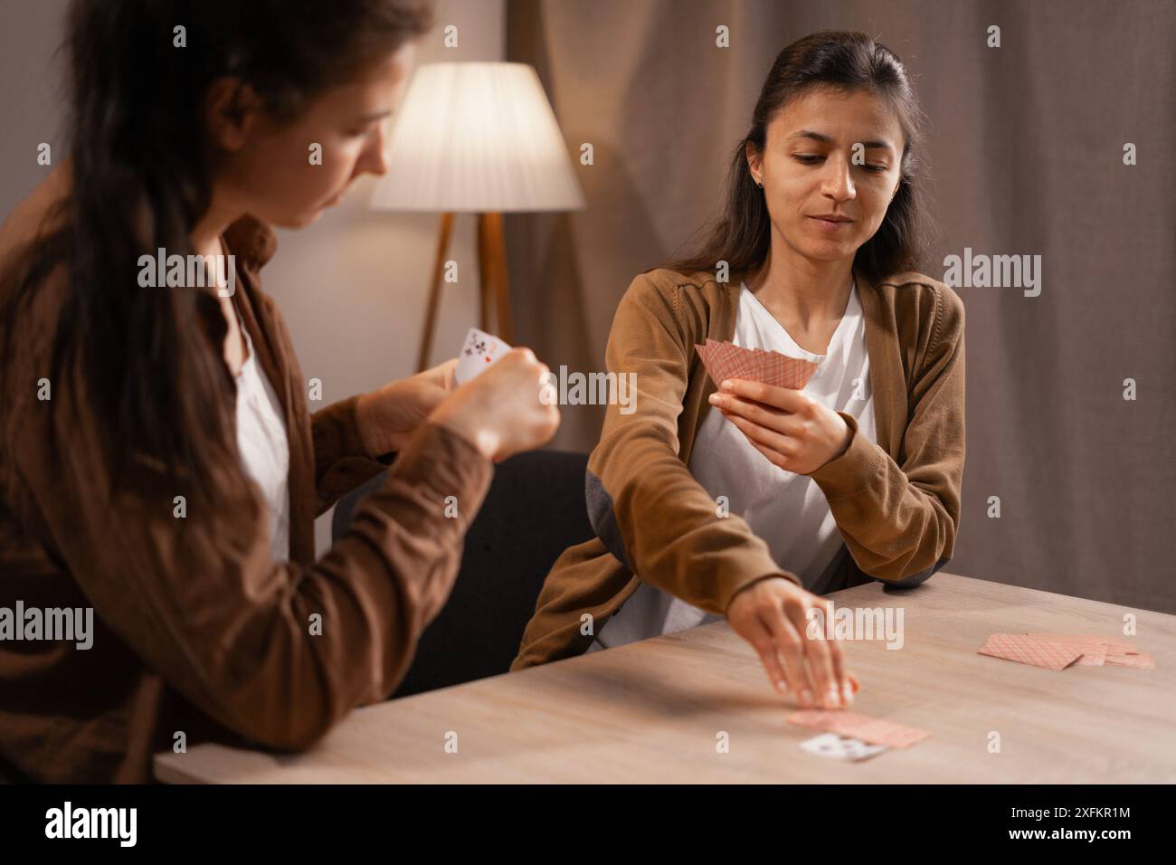 Card playing at home. Two friends woman playing cards in the living ...