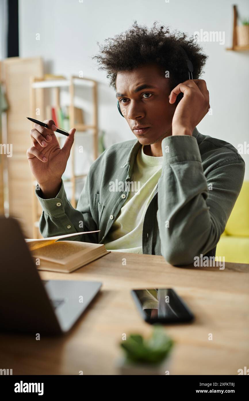 A young man of African American descent is focused on his laptop and ...