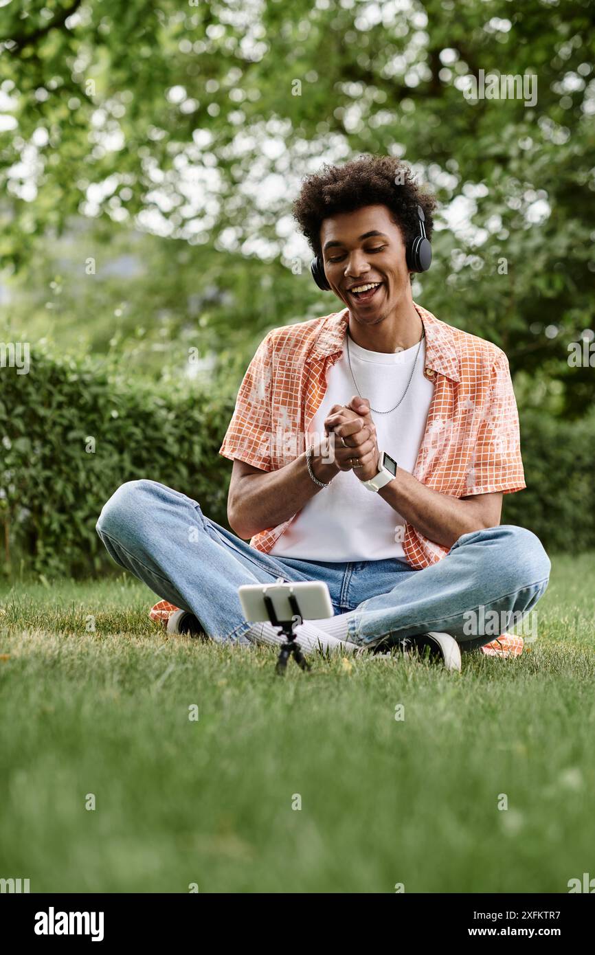 A young man of African American descent sitting on the grass, immersed ...