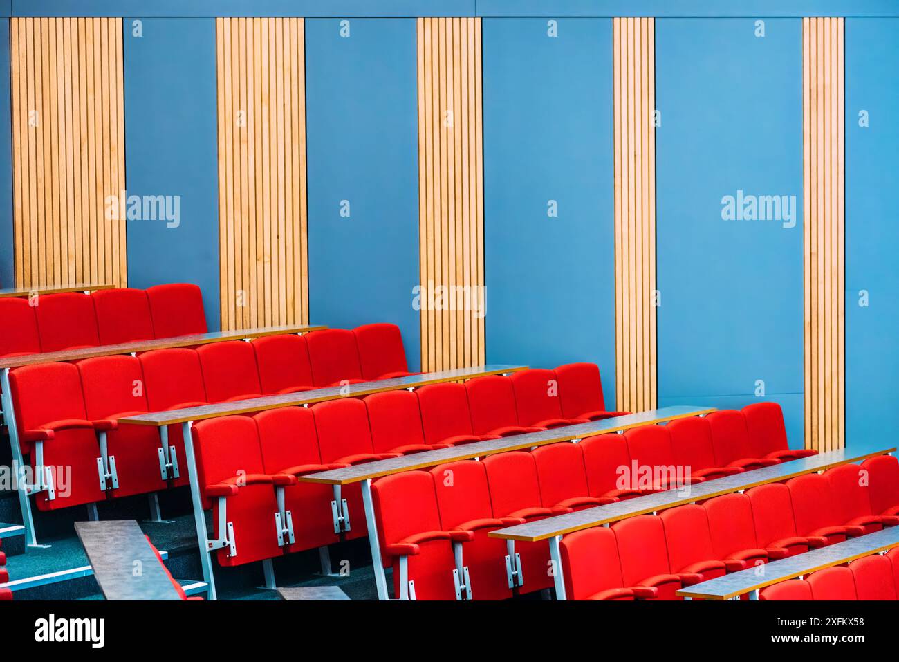 A wide-angle shot of a modern auditorium with rows of red seats and ...