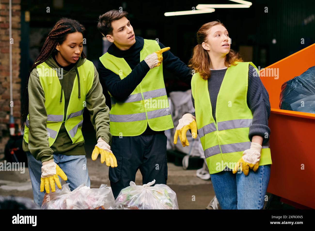 Group of young volunteers in gloves and safety vests sorting through a ...